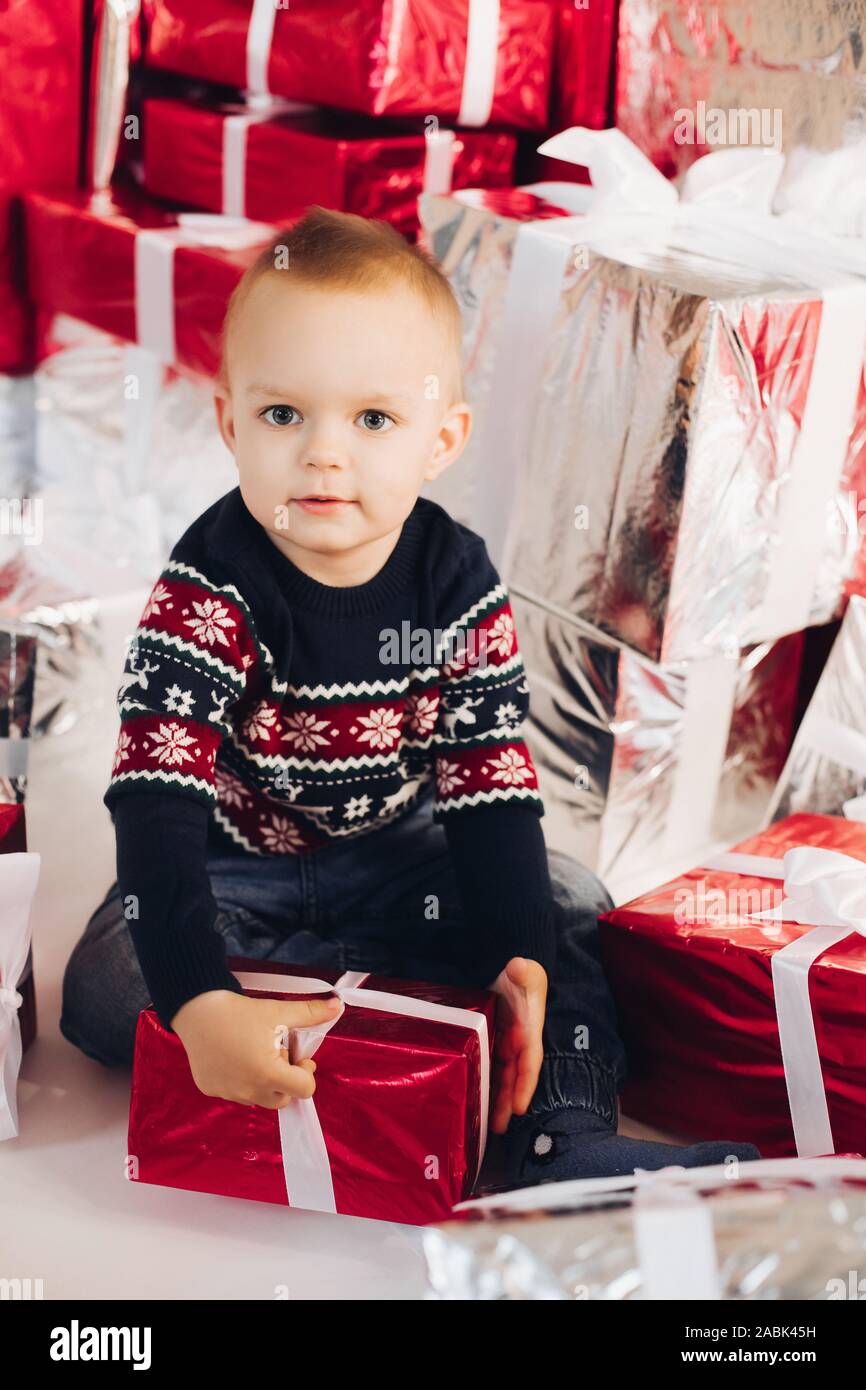Cute boy in sweater with wrapped red Christmas present Stock Photo - Alamy