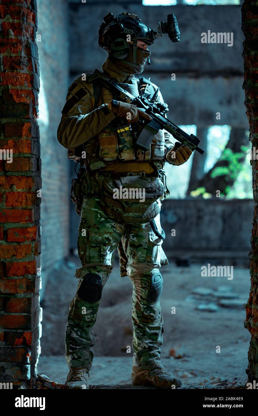 Airsoft man in uniform with machine gun and night-vision device on ...