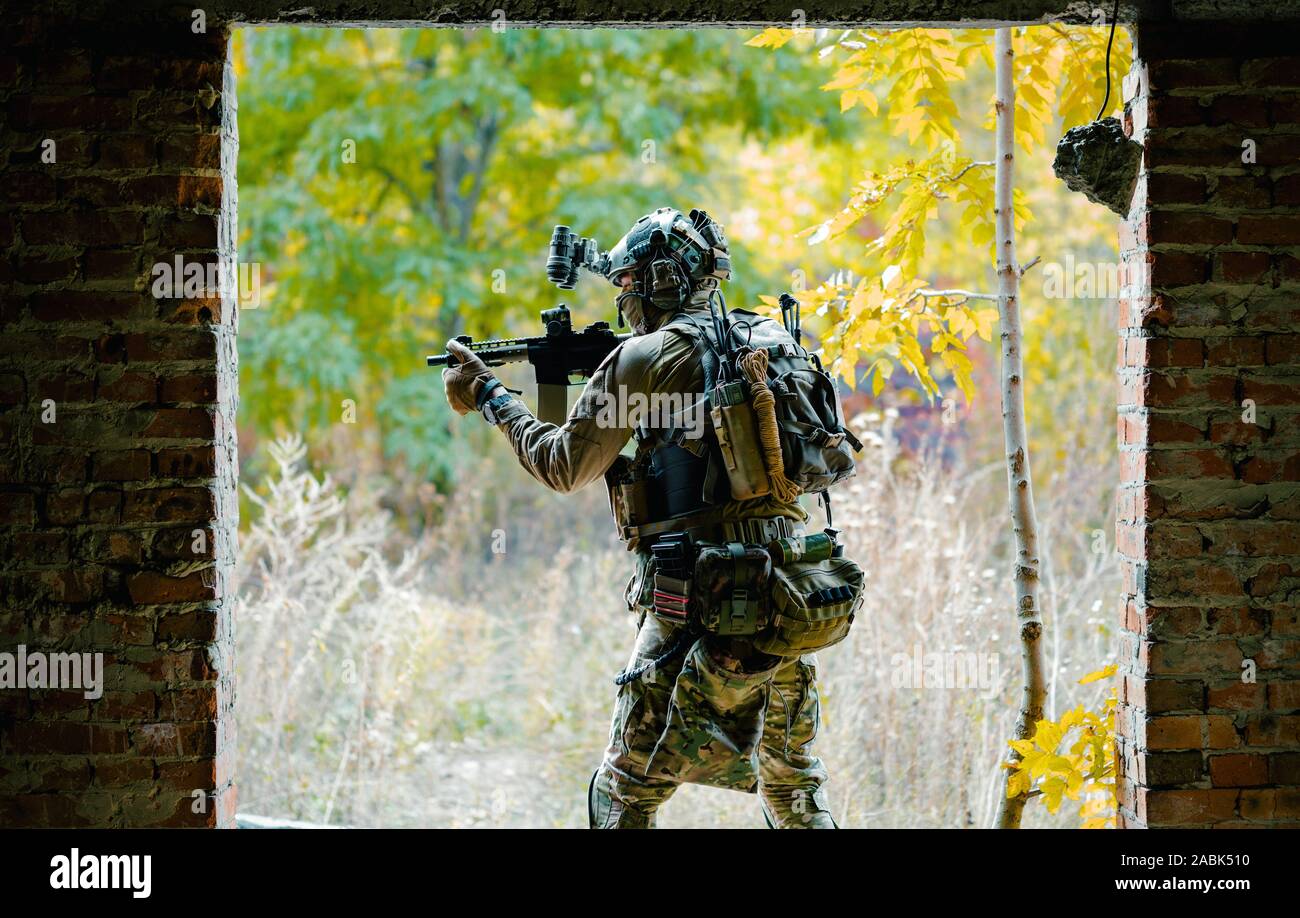 Airsoft man in uniform with machine gun and night-vision device on ...
