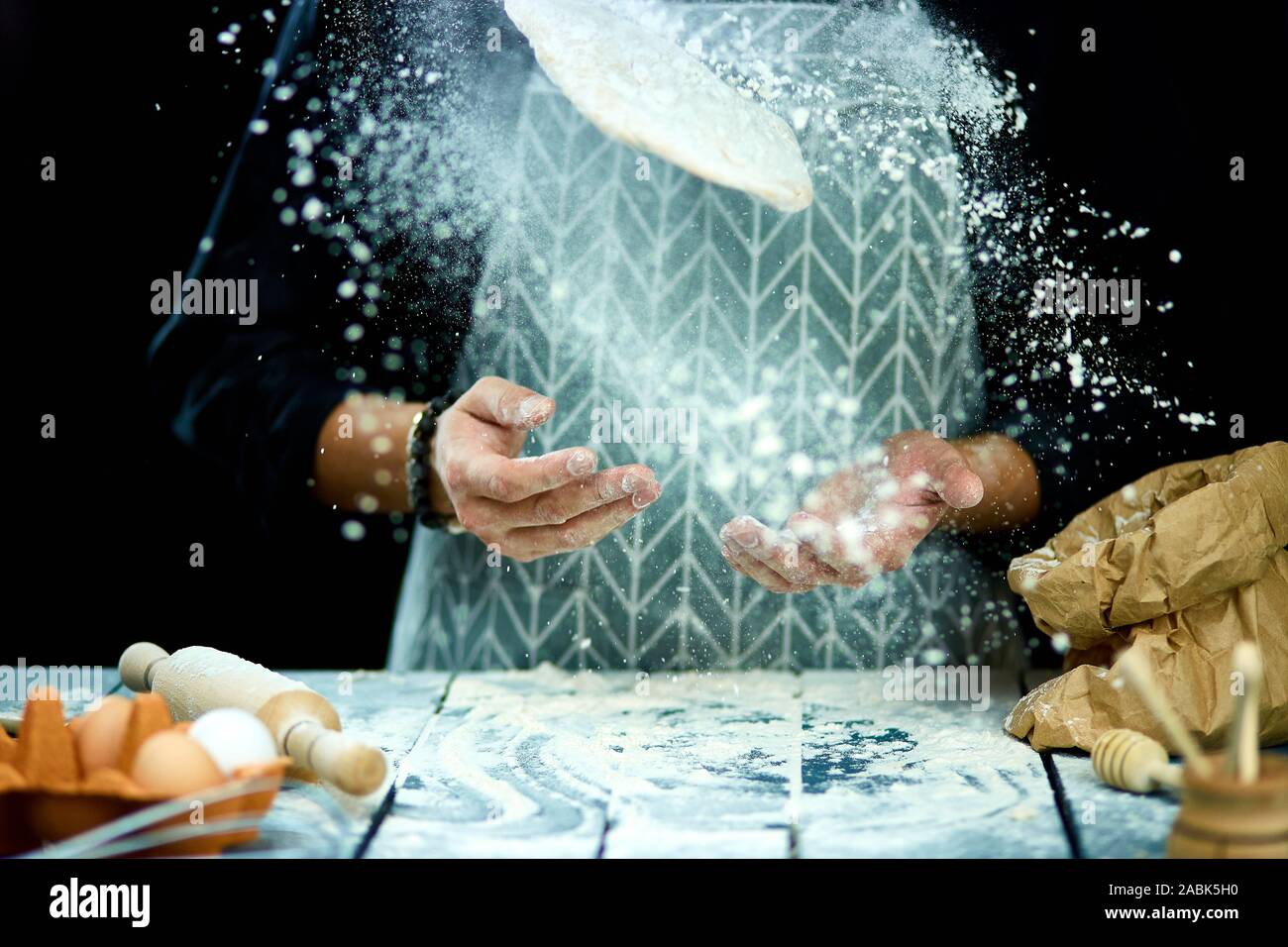 The man, chef cooks throws the dough, flying, freezing in motion. On a ...