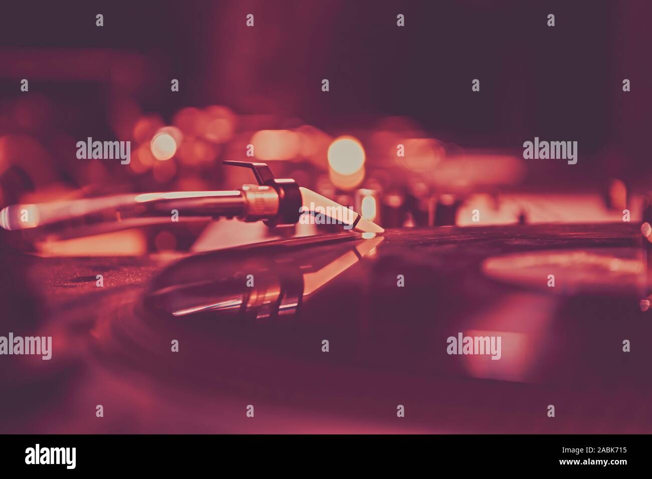 Retro dj turntable plays vinyl in red stage lights.Professional vintage ...