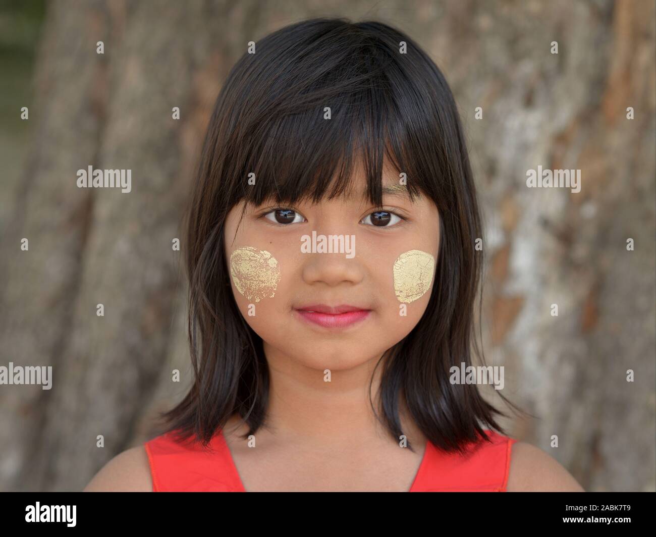 Young Burmese girl with patches of traditional thanaka face cosmetic on her cheeks poses for the ...