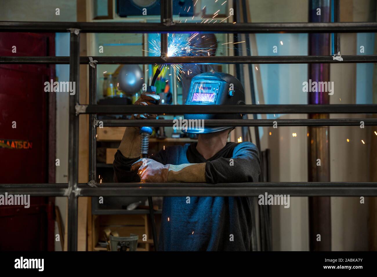 Front view of a focused welder designer wearing a helmet and wokring on ...