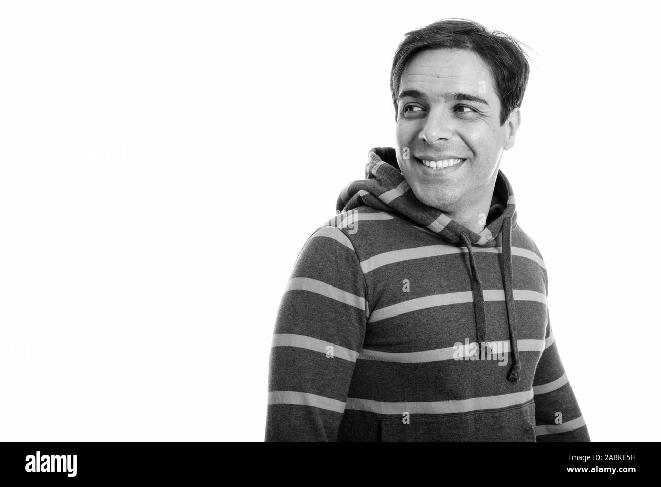 Studio shot of young happy Persian man smiling and thinking while ...