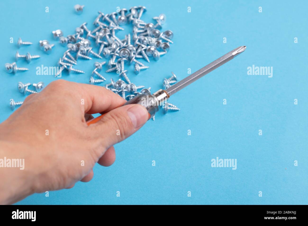 Man with screwdriver, metal screws background. Soft focus Stock Photo ...