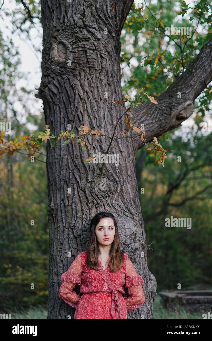 Woman standing next to a tree in park in golden autumn Stock Photo - Alamy