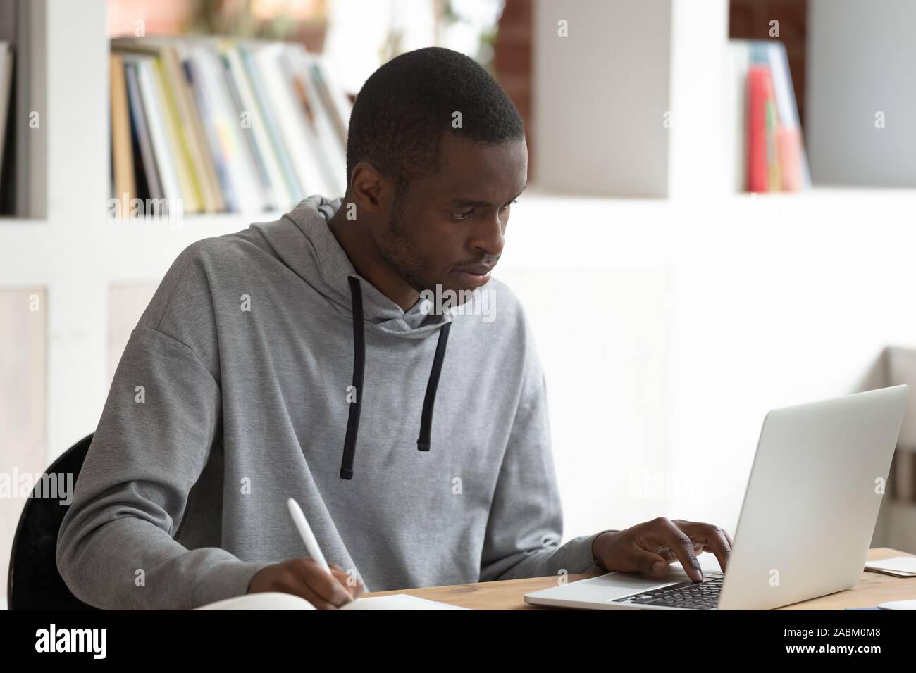 Serious black male student using laptop, busy with studying Stock Photo ...