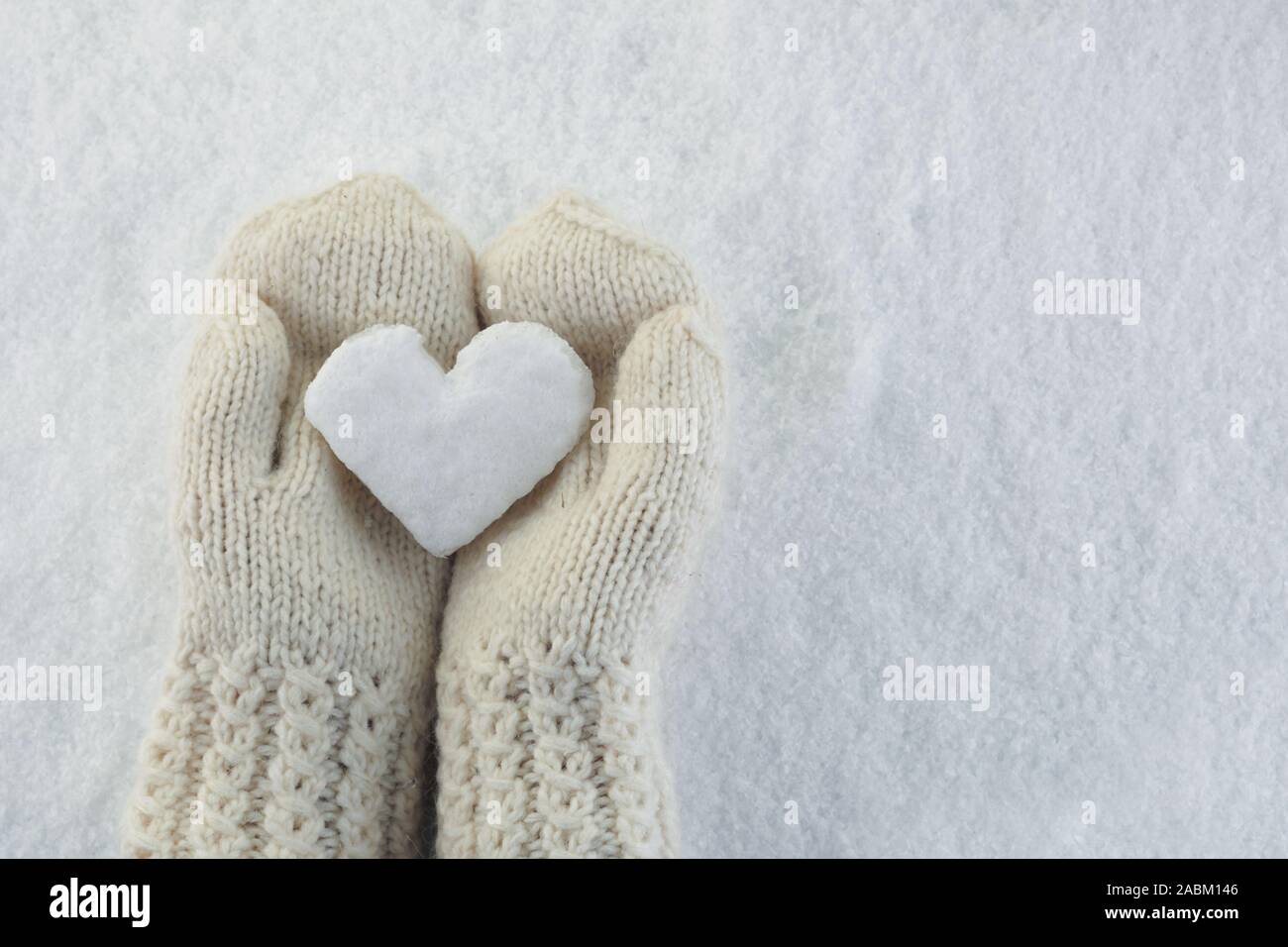 Snow Heart in Hands with Mittens on whit snow Stock Photo - Alamy