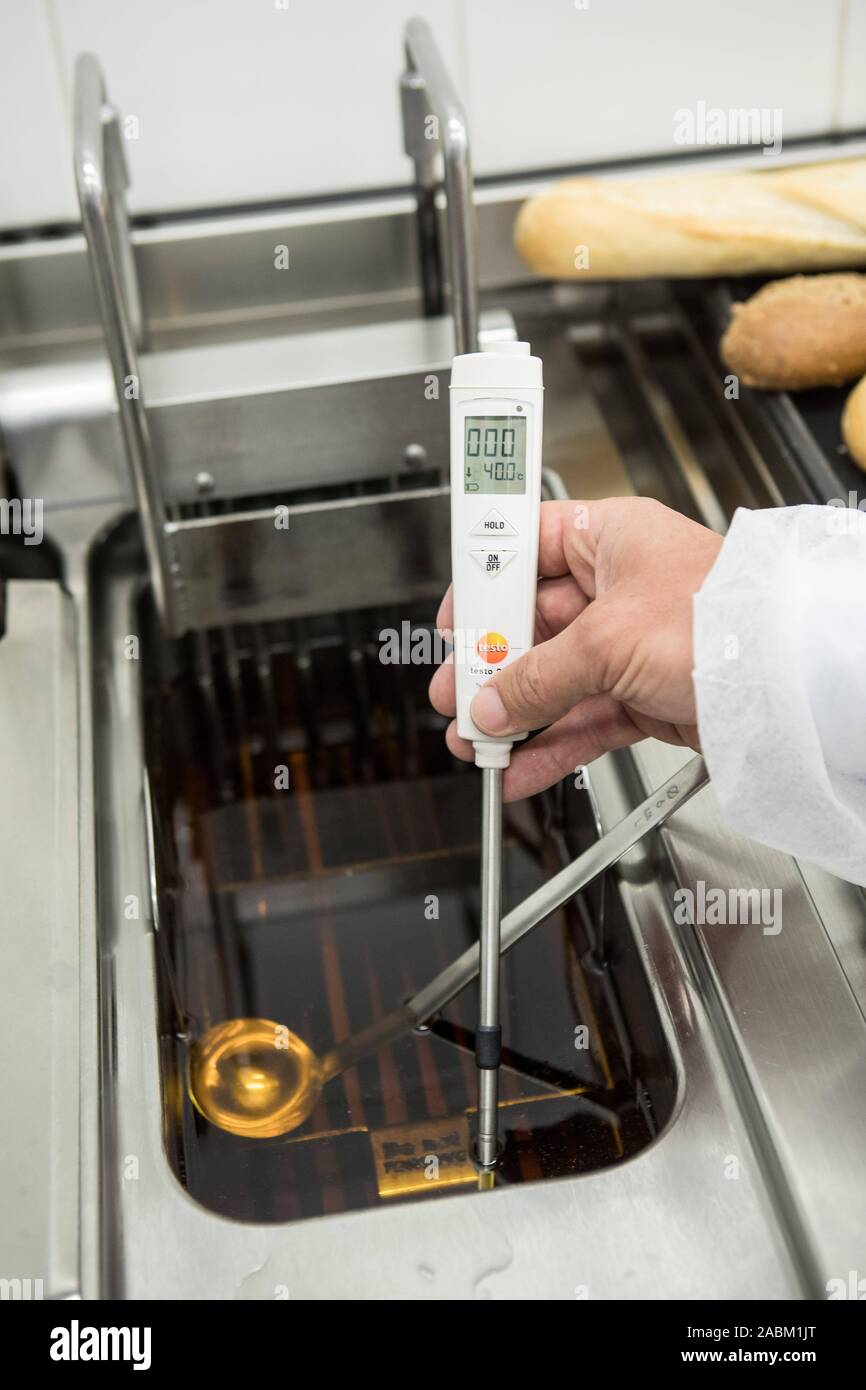 In a staged food inspection, fat is checked in the deep fryer. The ...