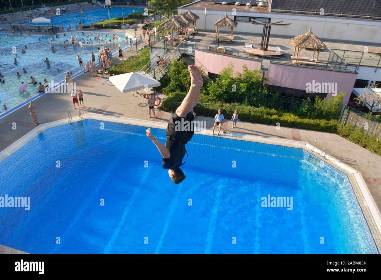 A youth jumps from a tower in the open-air swimming pool Unterhaching ...