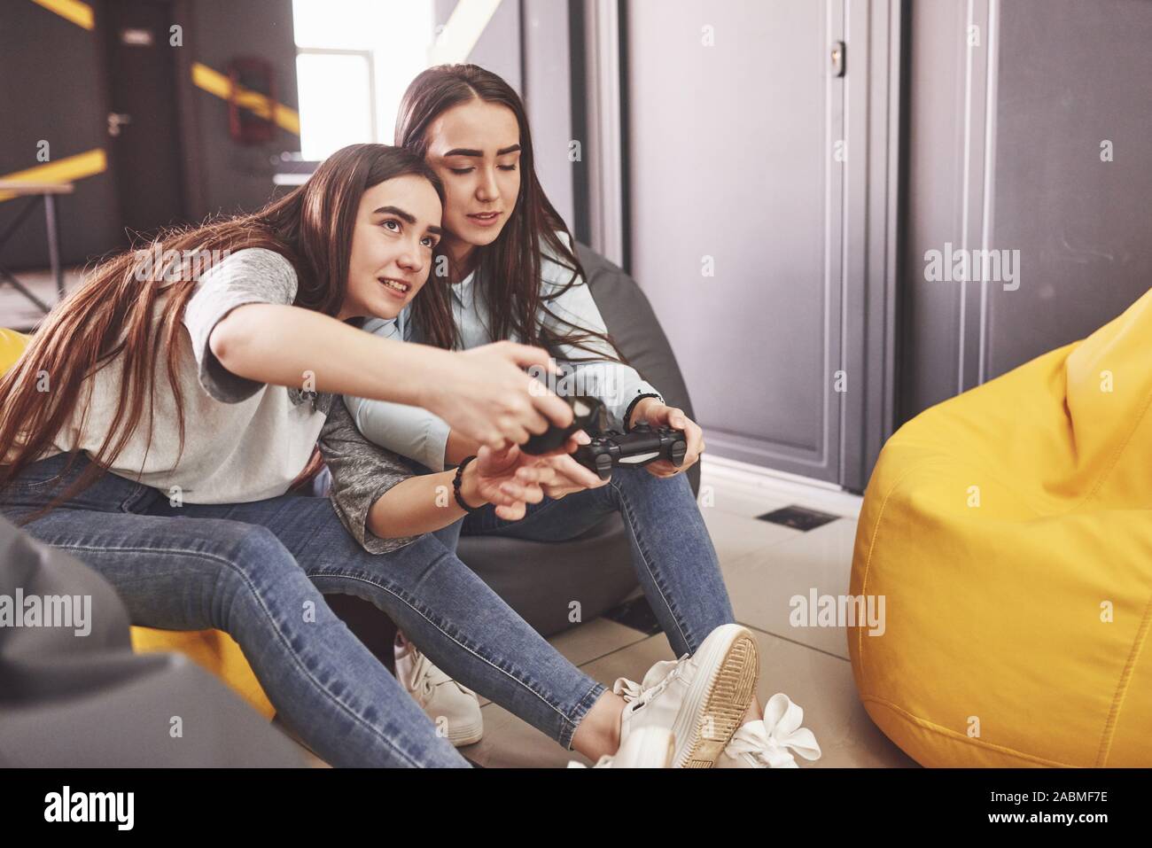 Twin sister sisters play on the console. Girls hold joysticks in their ...