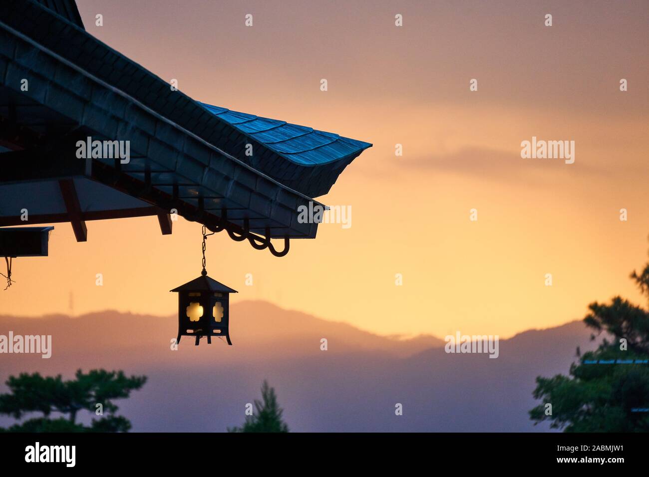 Traditional, old Japanese lantern hanging from the corner of a roof at ...