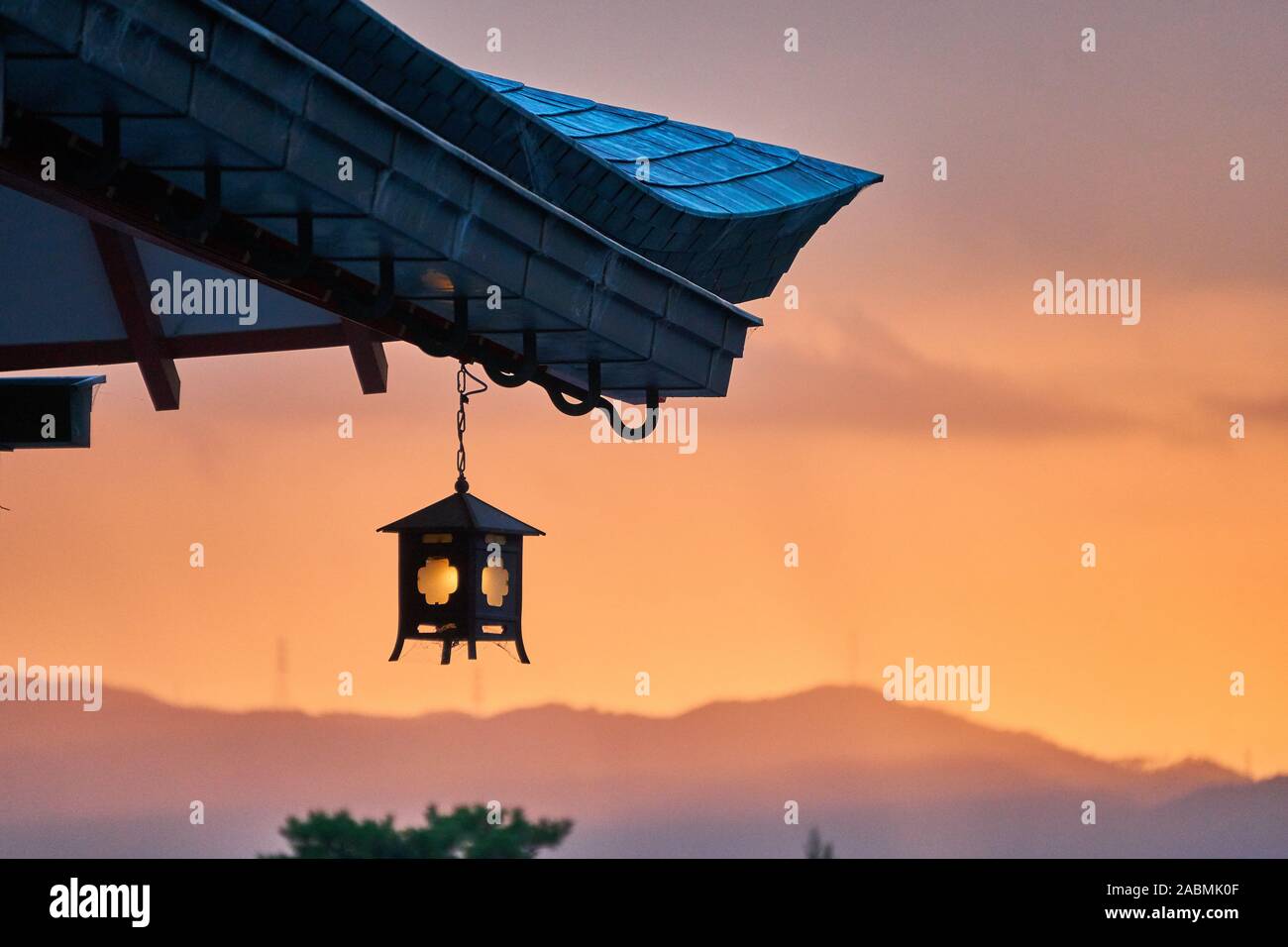Traditional, old Japanese lantern hanging from the corner of a roof at ...