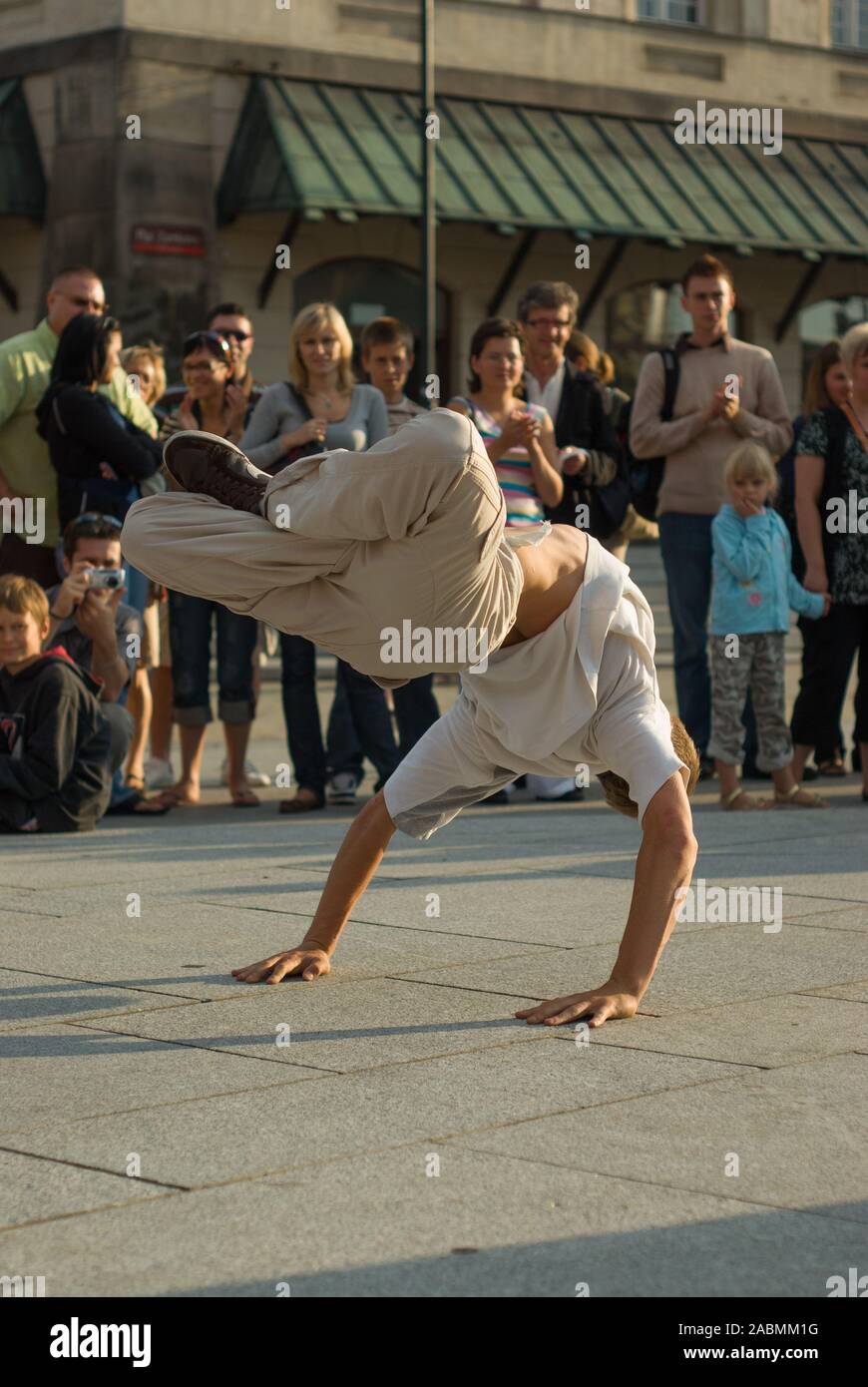 Street dancer standing on his hands in an equilibristic pose and ...