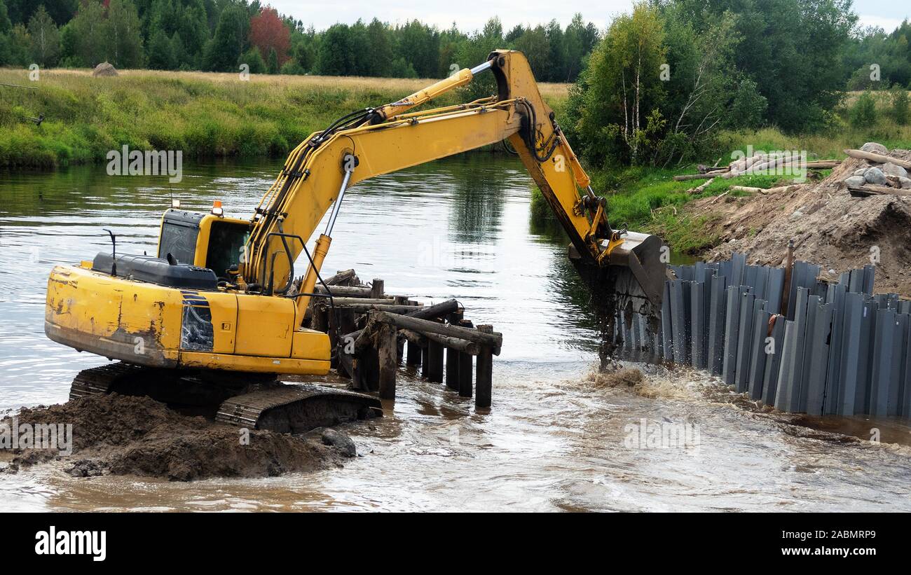 Excavator working in the small forest river, excavator bucket ...