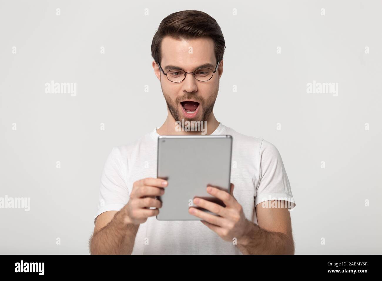 Excited Caucasian guy in glasses feel shocked using tablet Stock Photo ...