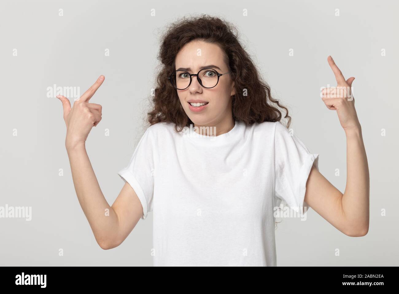 Confused millennial girl twist finger feel puzzled with problem Stock ...