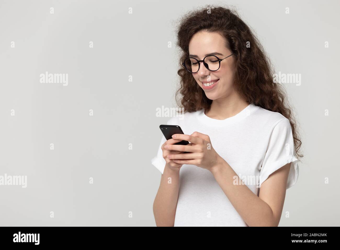 Smiling millennial girl texting using modern cellphone Stock Photo - Alamy