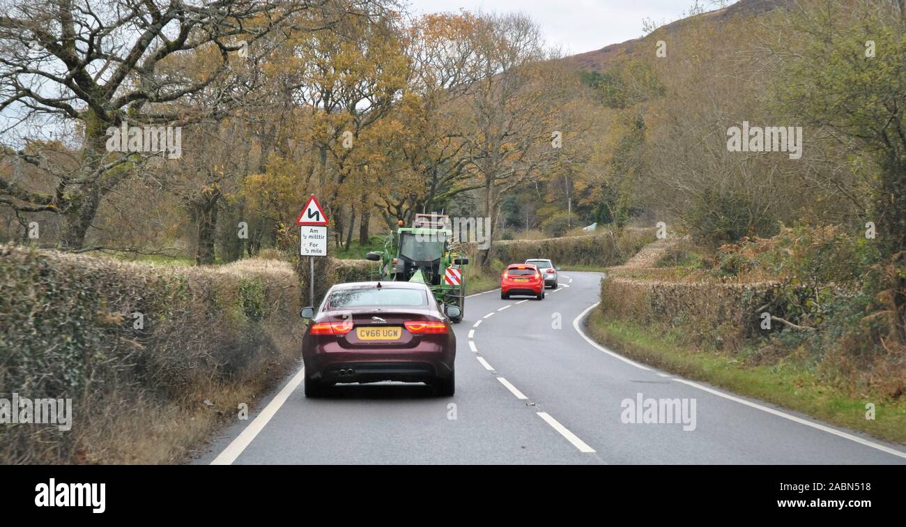 Cars passing an agricultural tractor on a winding road Stock Photo - Alamy