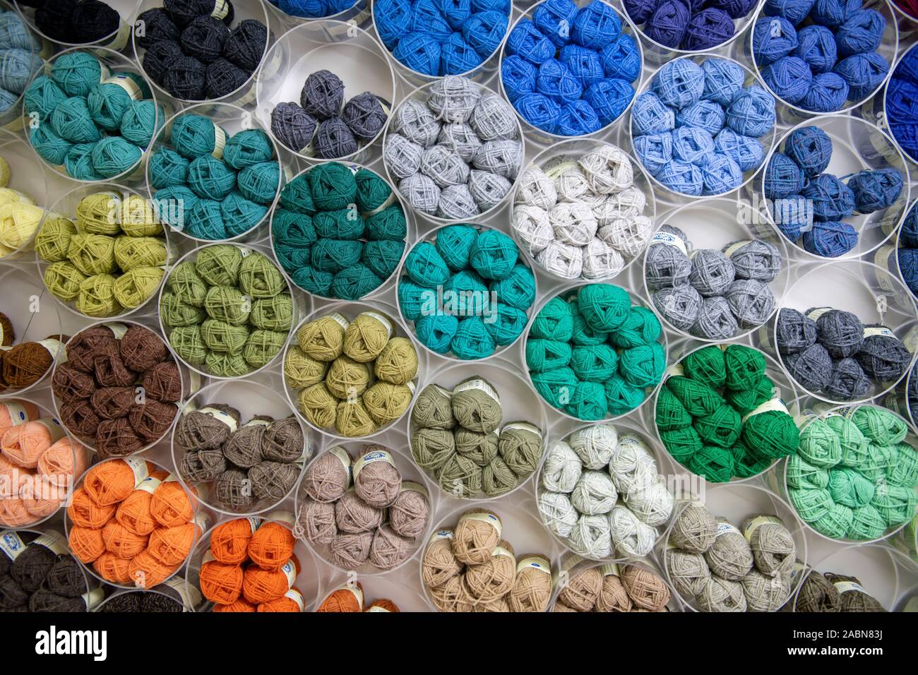 Selection of different coloured wool yarn on display on a wall in ...