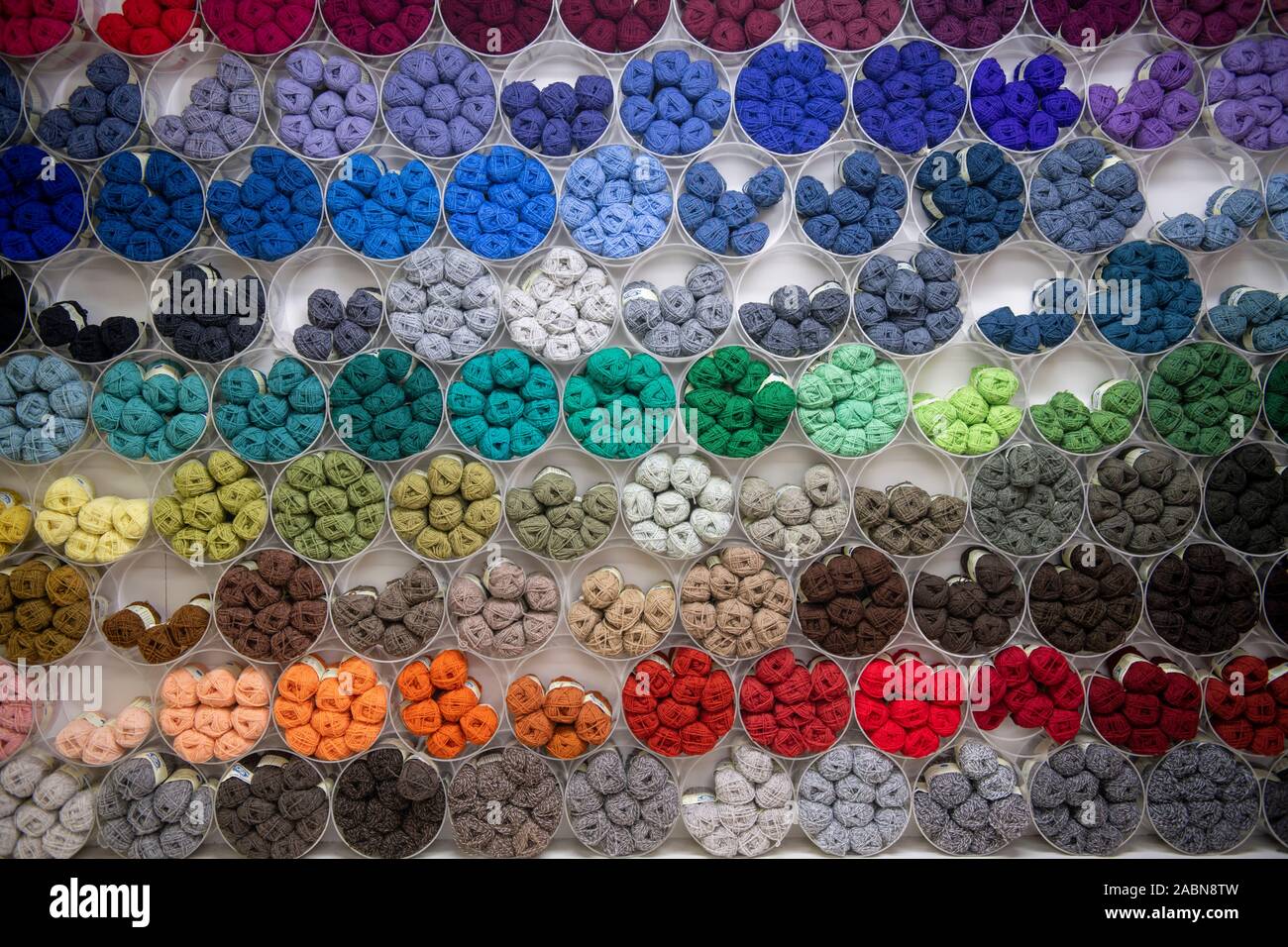 Selection of different coloured wool yarn on display on a wall in ...