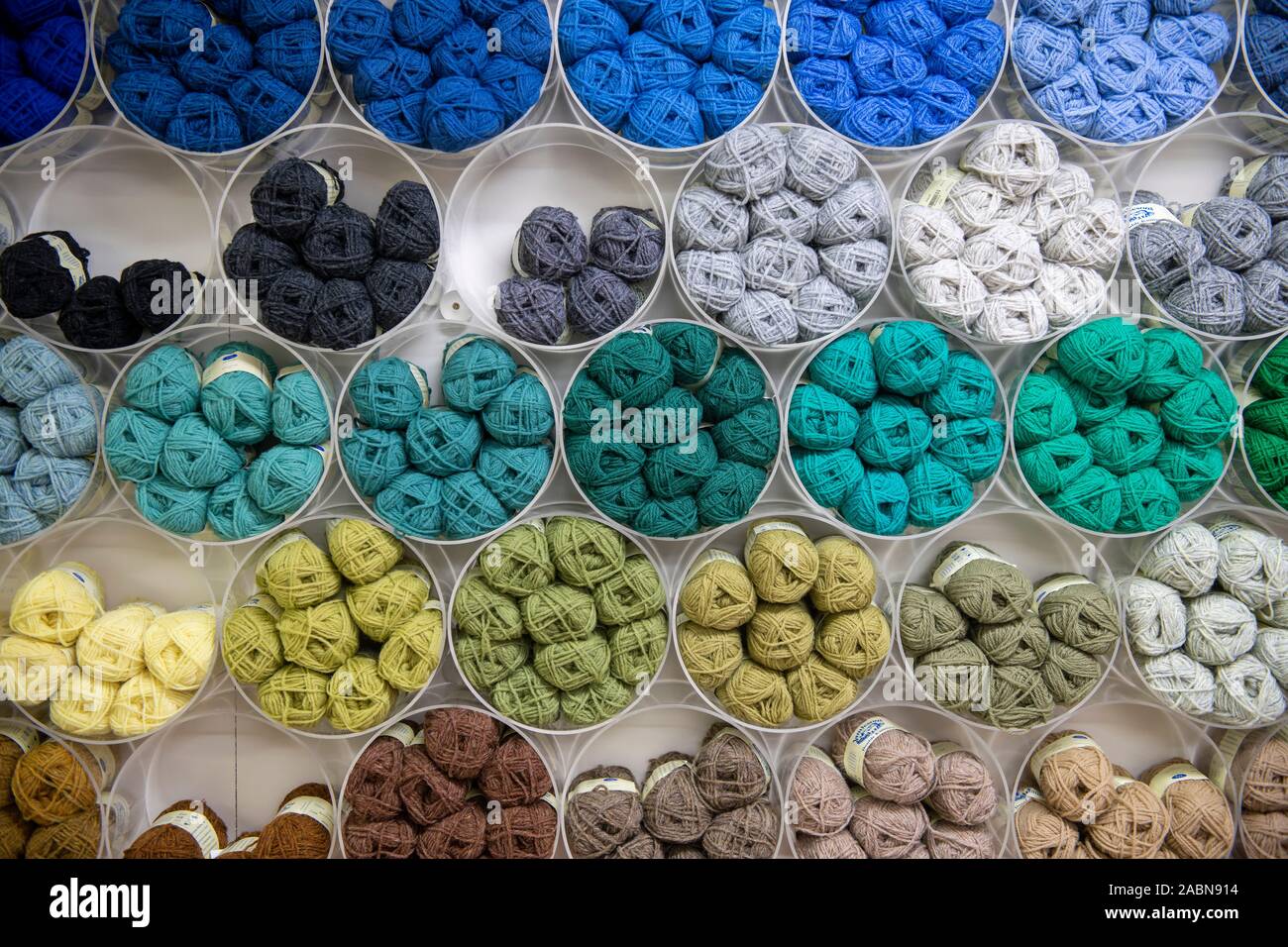 Selection of different coloured wool yarn on display on a wall in ...