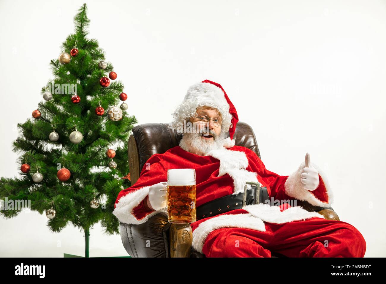 Santa Claus drinking beer near the Christmas tree, congratulating ...