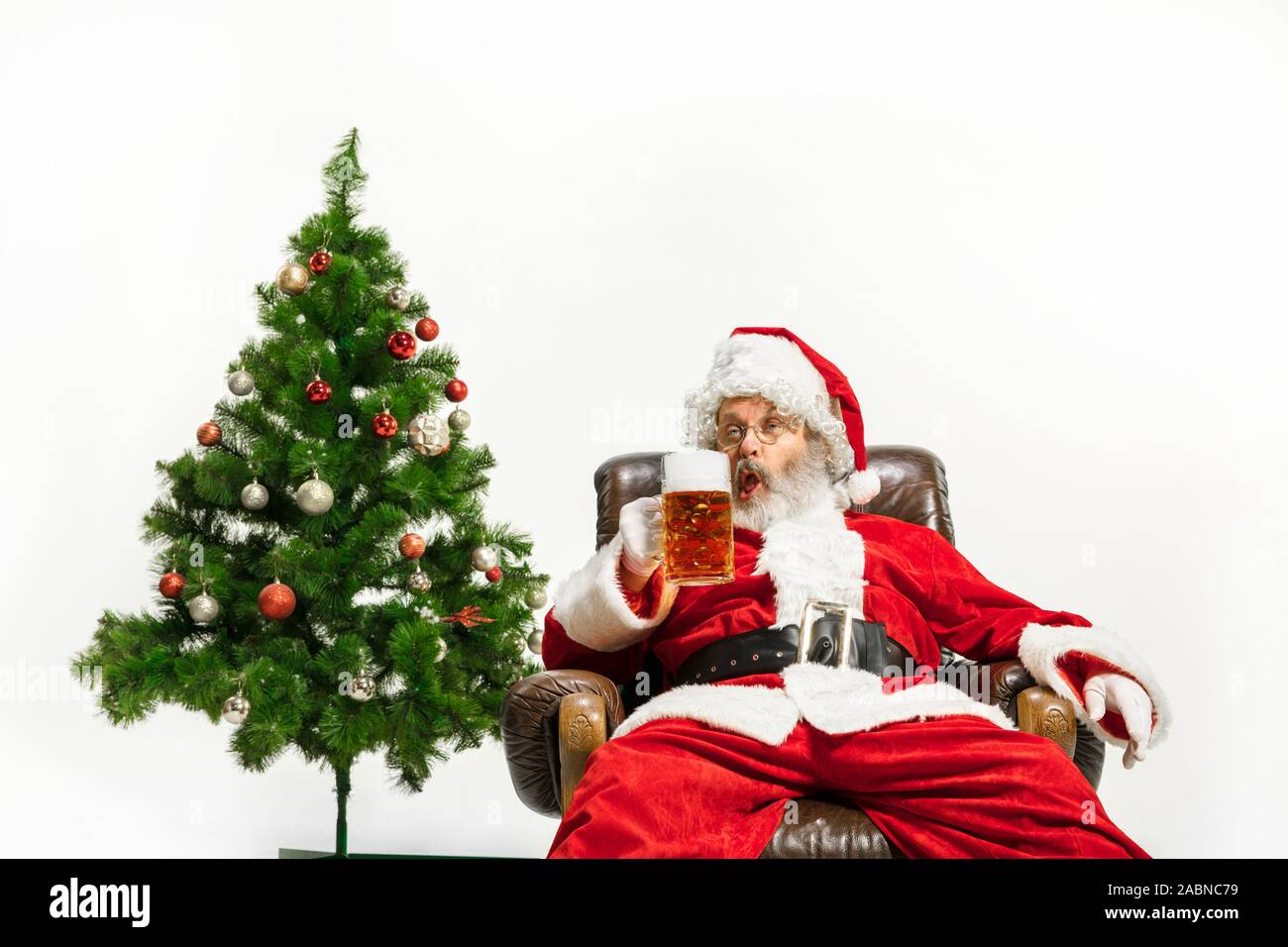 Santa Claus drinking beer near the Christmas tree, congratulating ...