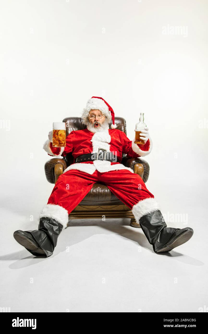 Santa Claus drinking beer sitting on armchair, congratulating, looks ...