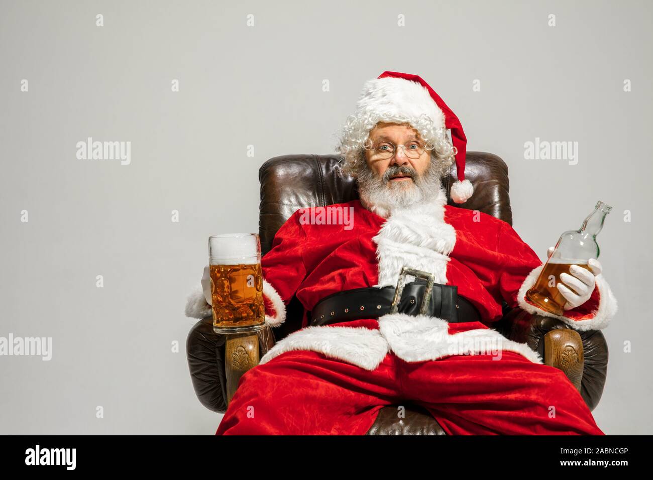 Santa Claus drinking beer sitting on armchair, congratulating, looks ...