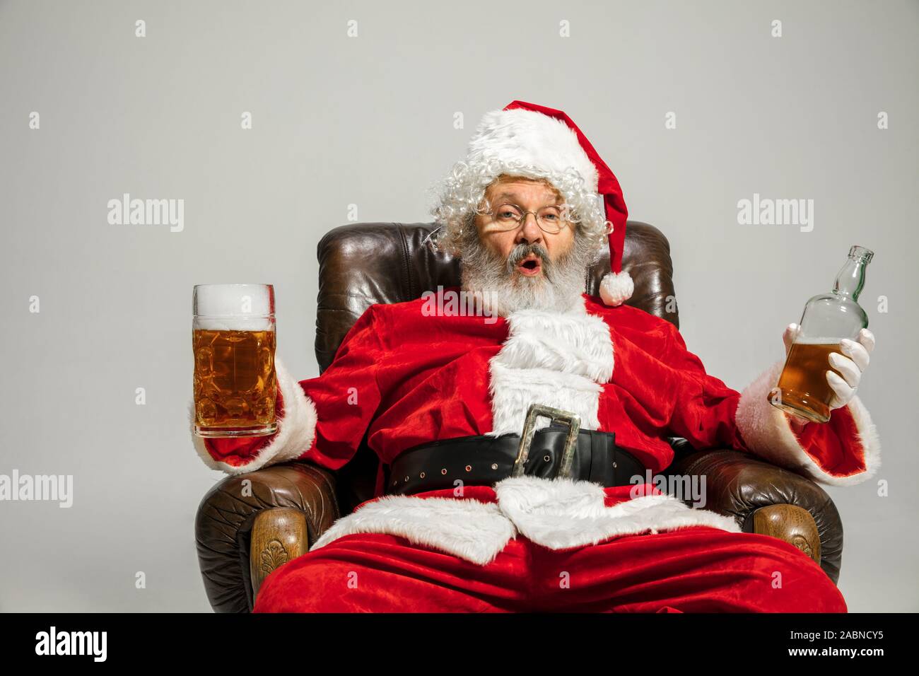 Santa Claus drinking beer sitting on armchair, congratulating, looks ...