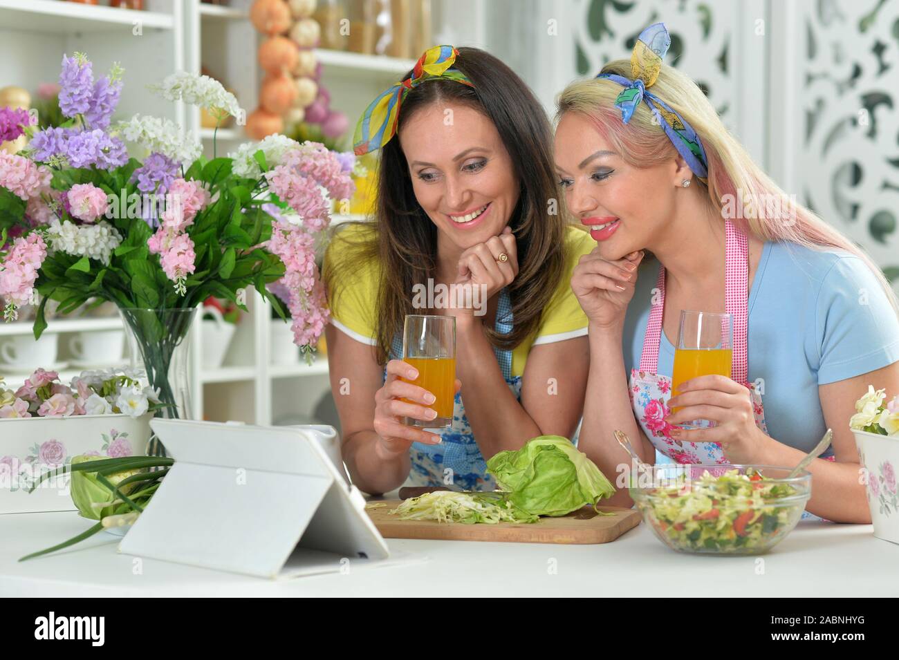 Two beautiful young women cooking together in kitchen Stock Photo - Alamy