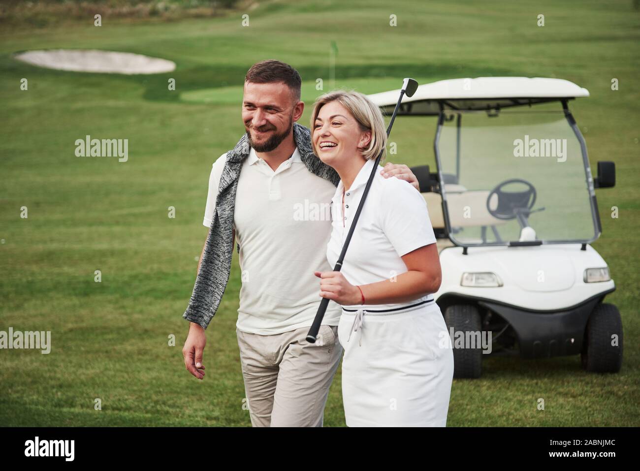 Two golfers, a woman and a man, go together to the next hole. A student ...