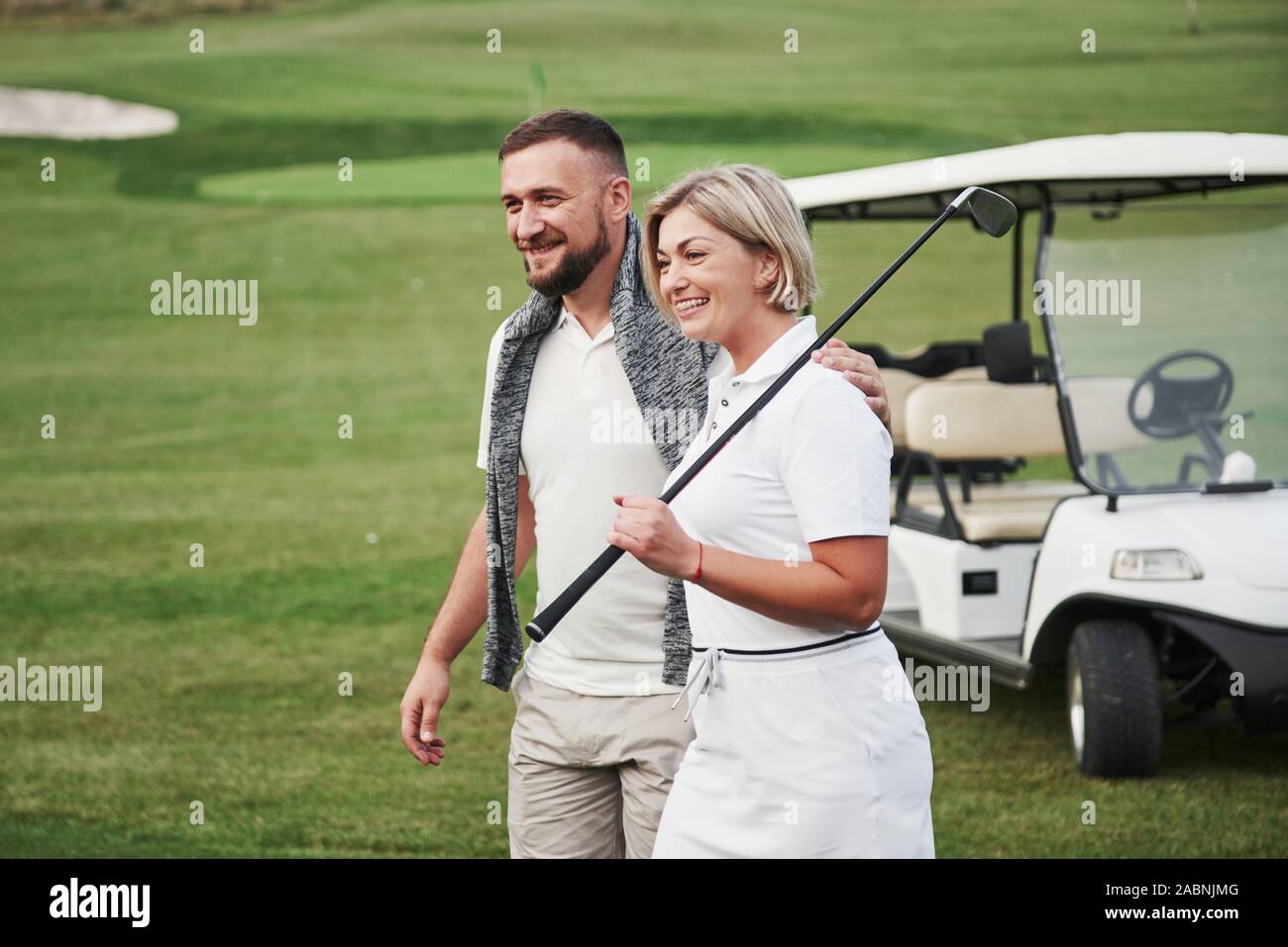 Two golfers, a woman and a man, go together to the next hole. A student ...