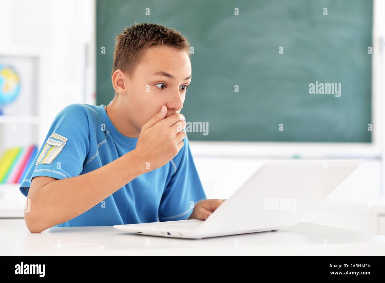 Portrait of a surprised boy using laptop in room Stock Photo - Alamy