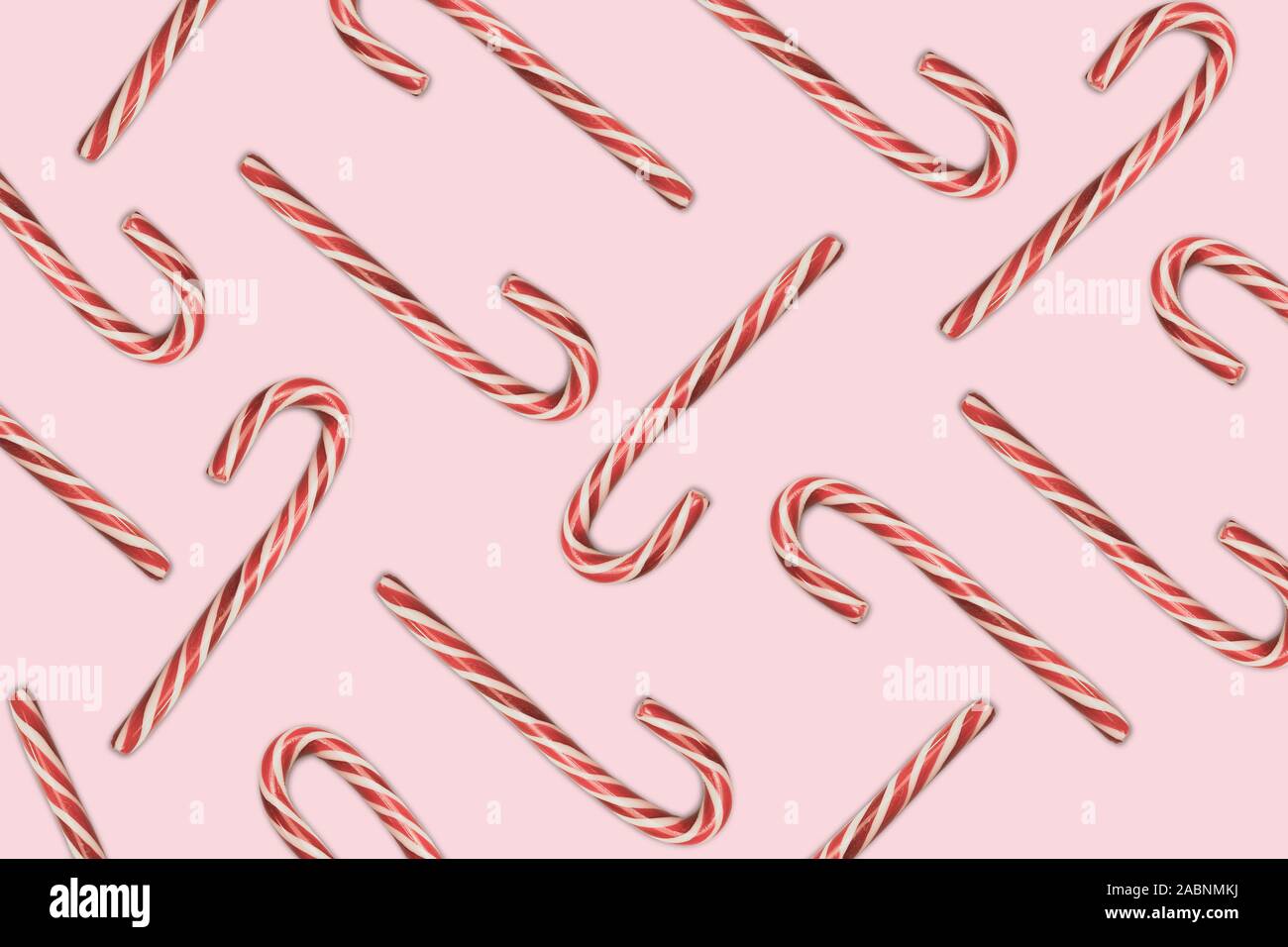 Beautiful striped hard candy cane staff on a pink table background ...