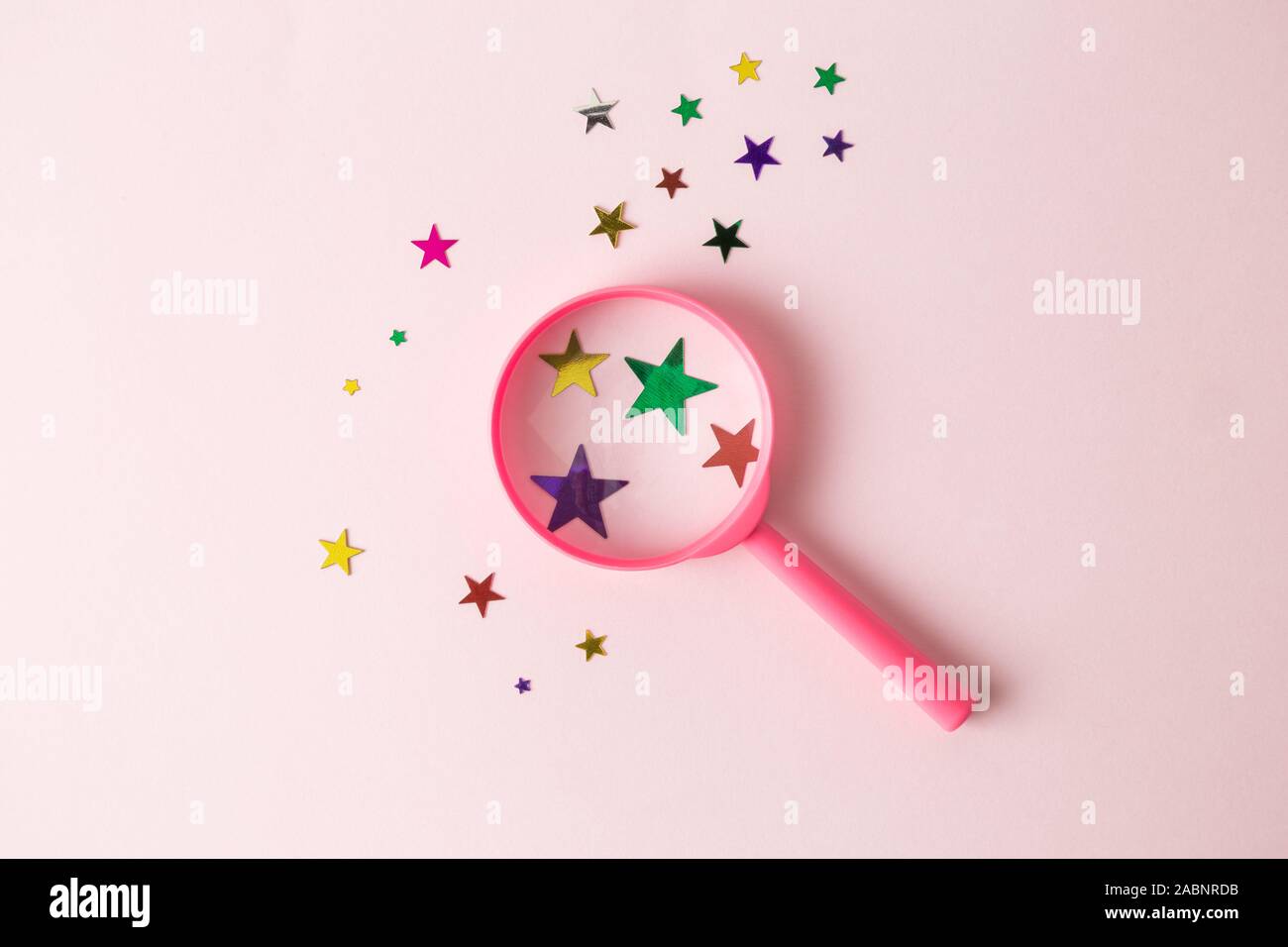 Flat lay of magnifying glass with colorful stars on pastel background ...