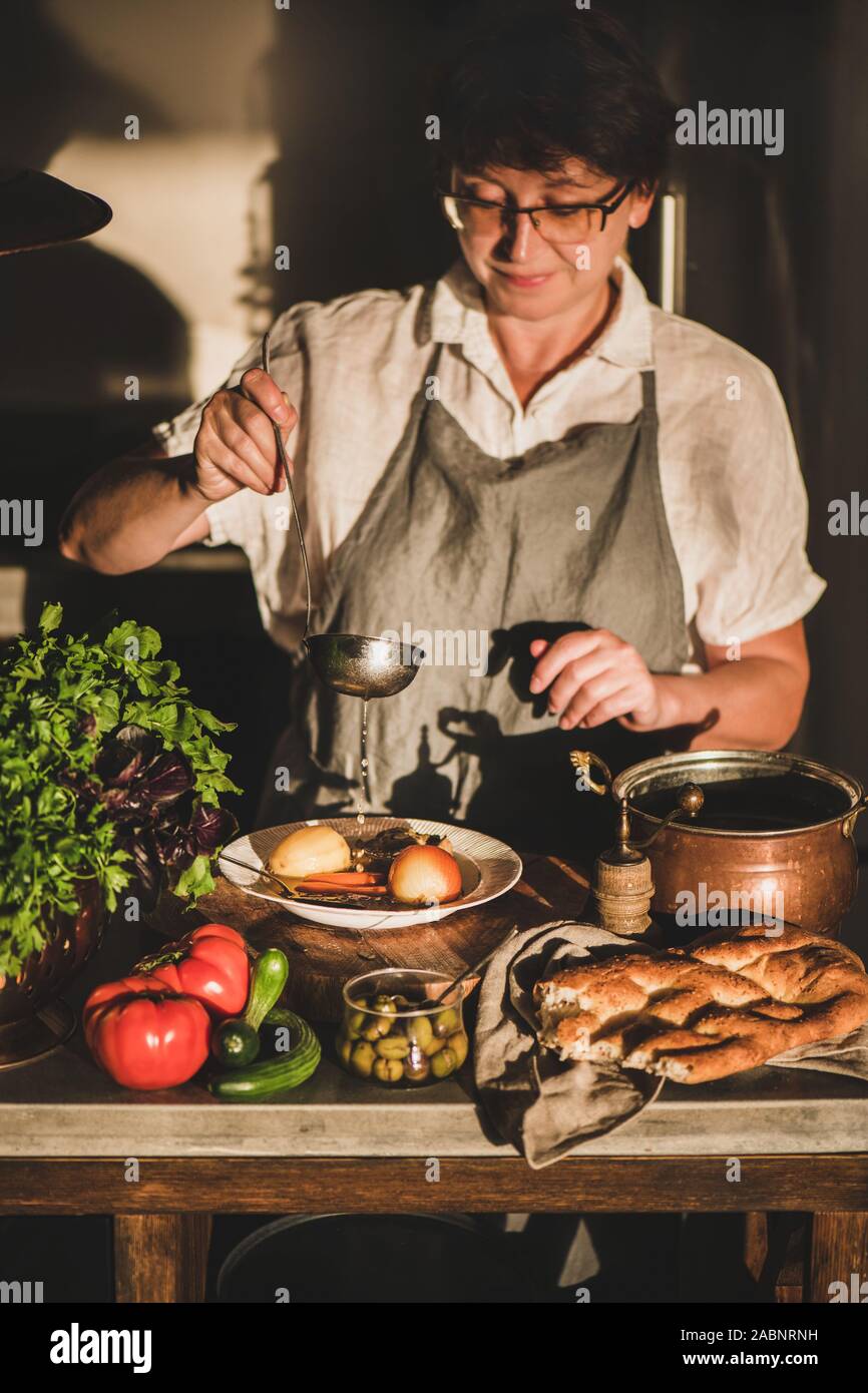 Woman cooking Turkish traditional meat soup Haslama with vegetables ...
