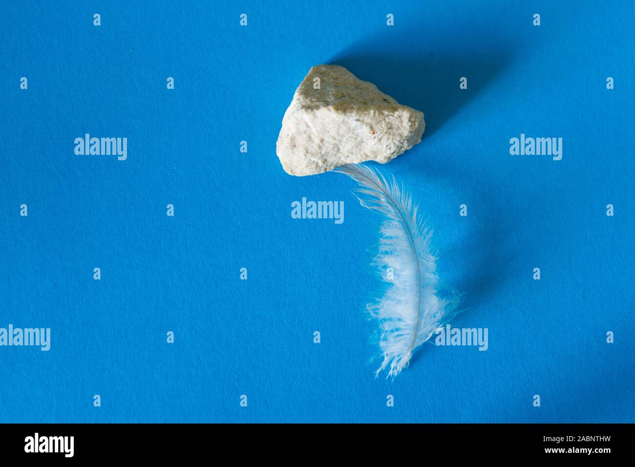 Stone on feather. Strenght and balance concept Stock Photo - Alamy