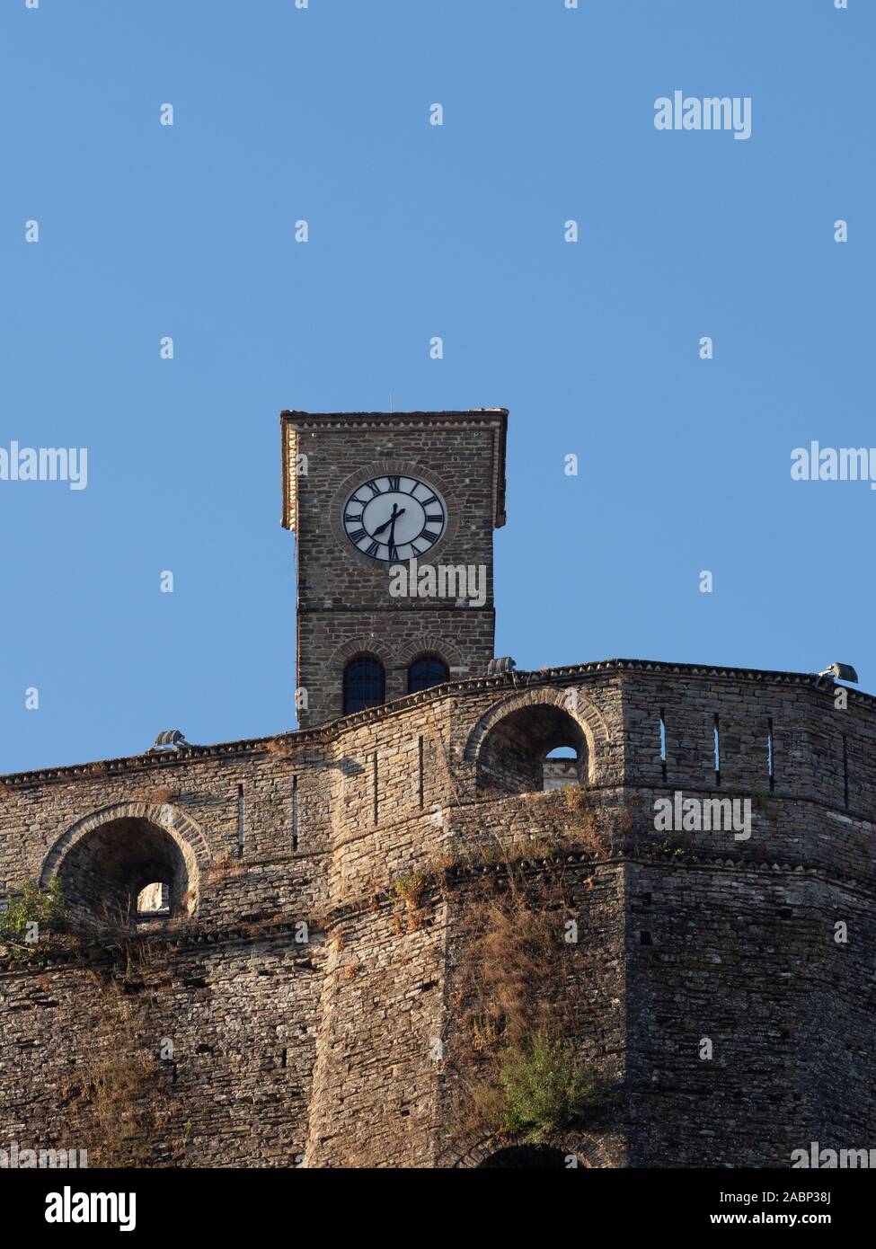 Stone clock tower and fortress with arched windows and arrow slits ...