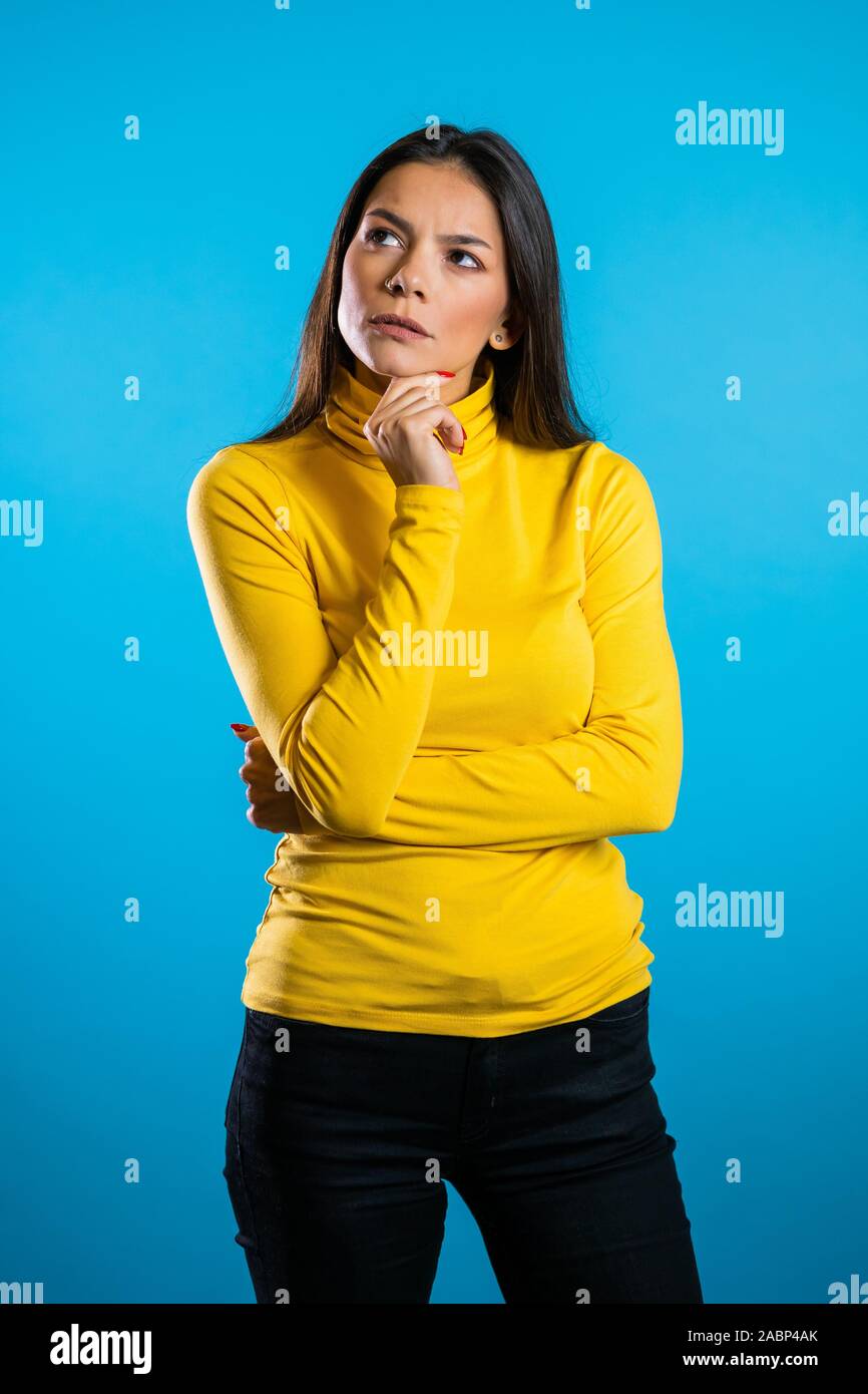 Thinking woman looking around on blue background. Worried contemplative ...