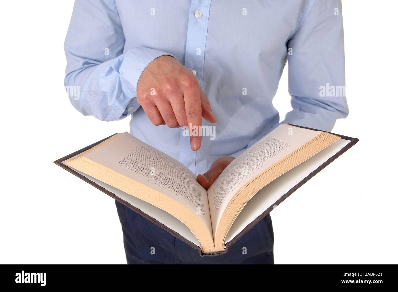 A young man standing is the studio holding an open book and pointing at ...