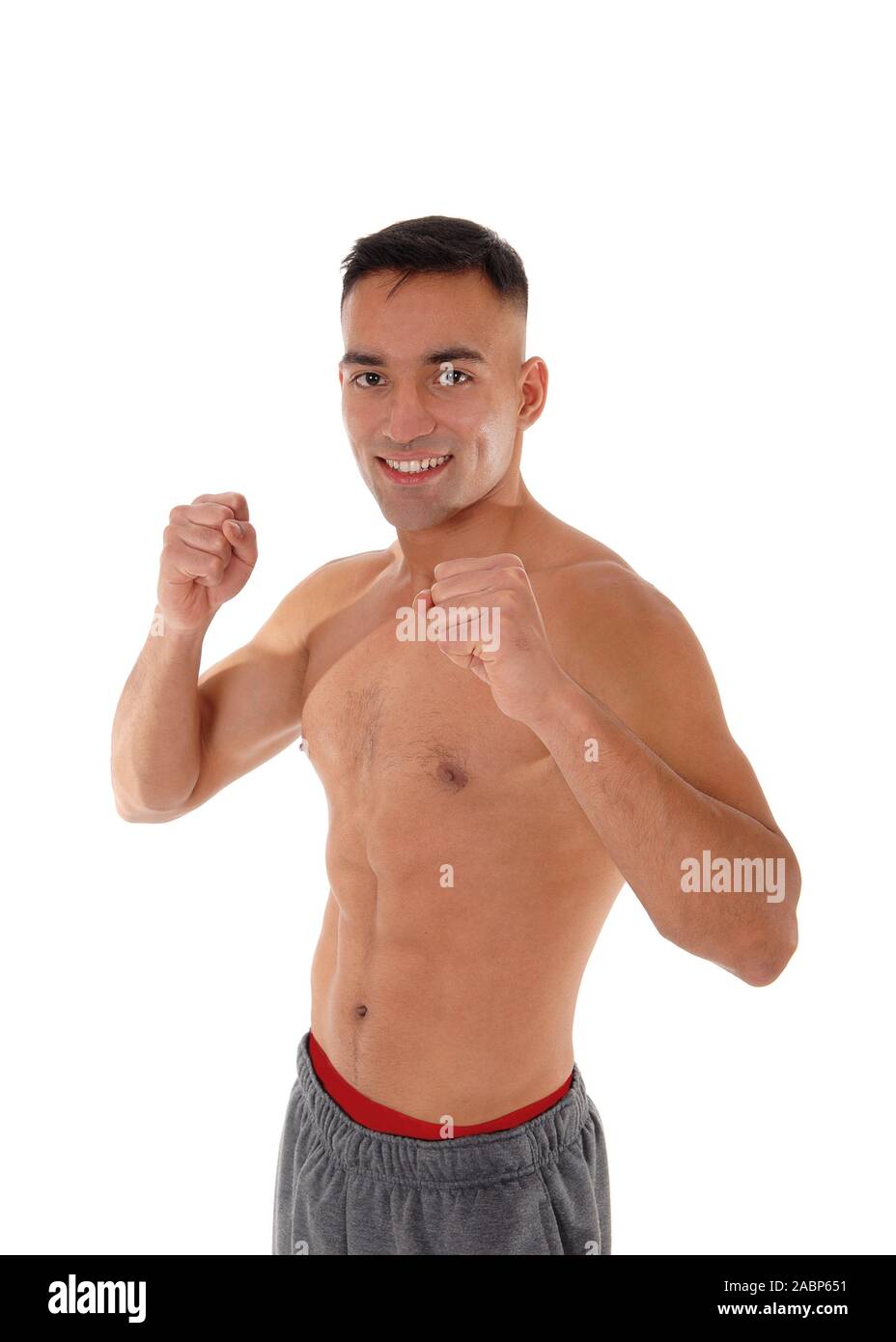 A handsome east Indian man standing without a shirt making fists with ...