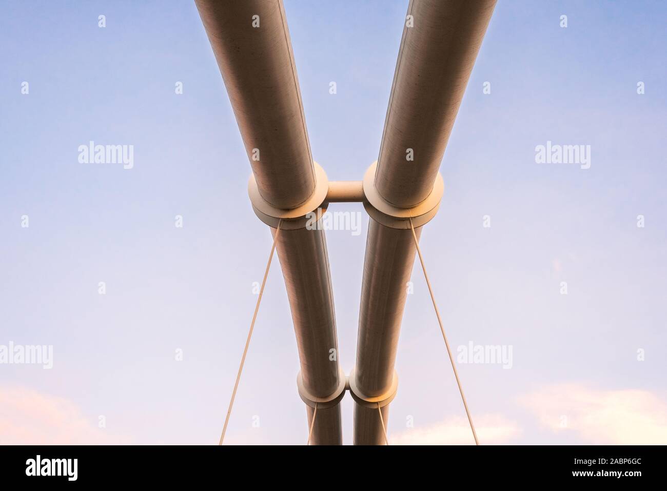 Symmetrical steel pipes supporting a suspension bridge over a river ...