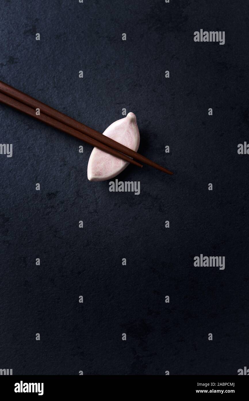 Wooden chopsticks and chopstick rest on black stone background. Top ...
