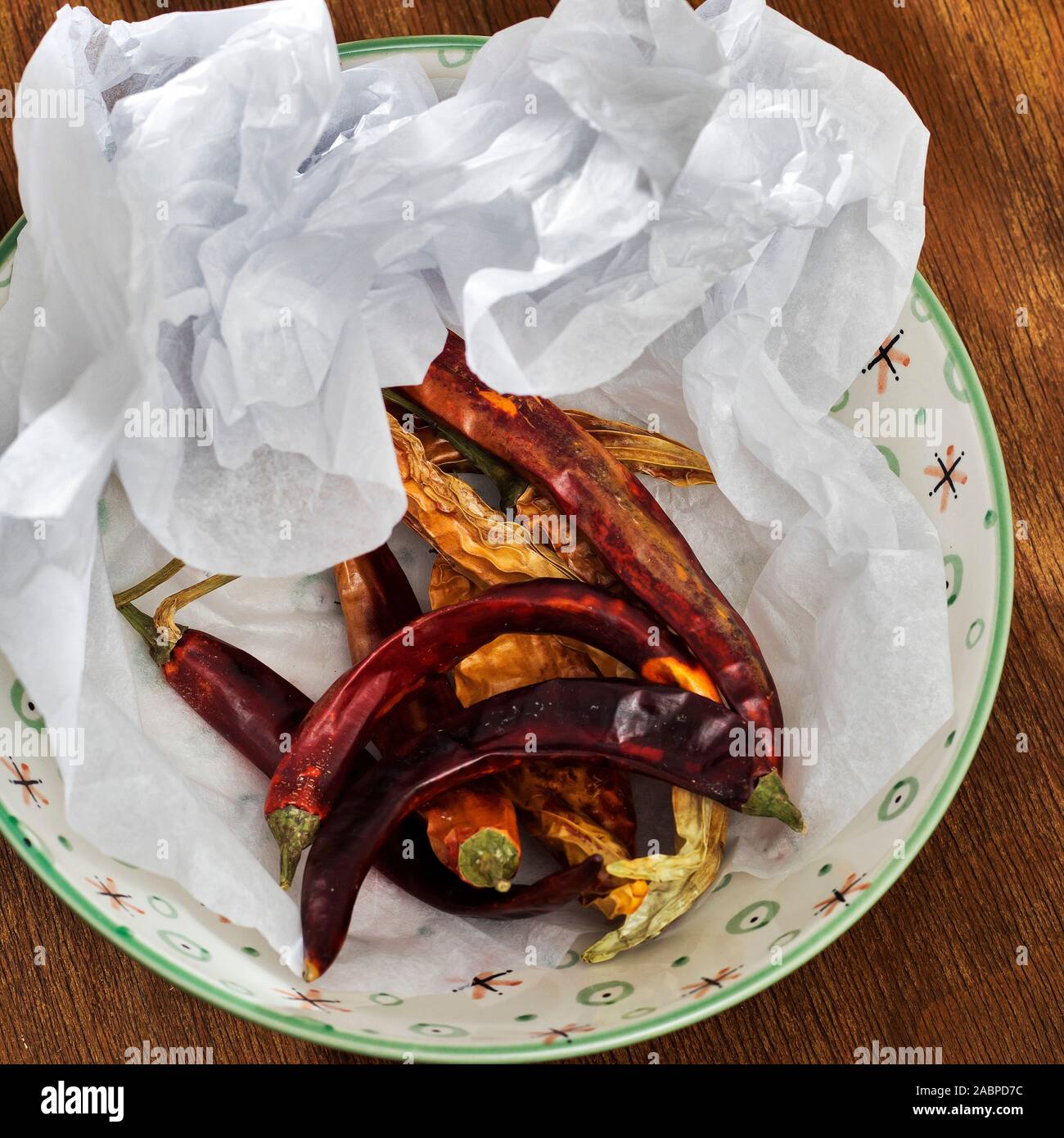 Dried hot peppers in crumpled craft paper in the kitchen as a ...