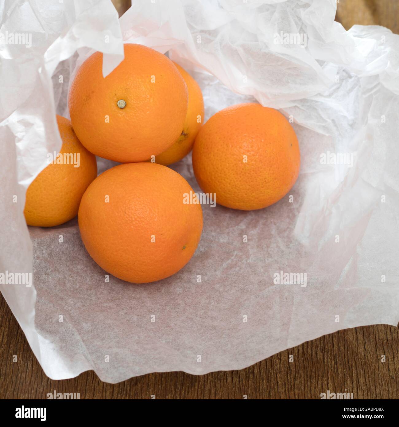 Tangerines in yellow crumpled craft paper on a dark wooden kitchen ...