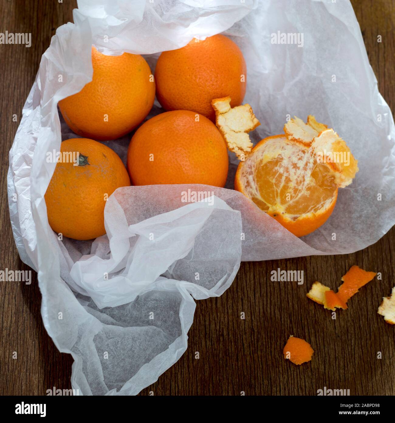 Tangerines in yellow crumpled craft paper on a dark wooden kitchen ...