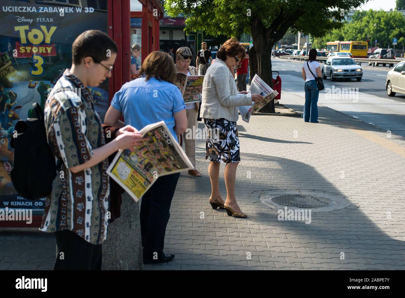 People reading newspapers while waiting for a public transport bus ...