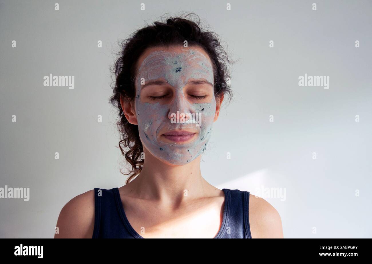 A woman pampering herself with a fresh blueberry face mask up-close ...
